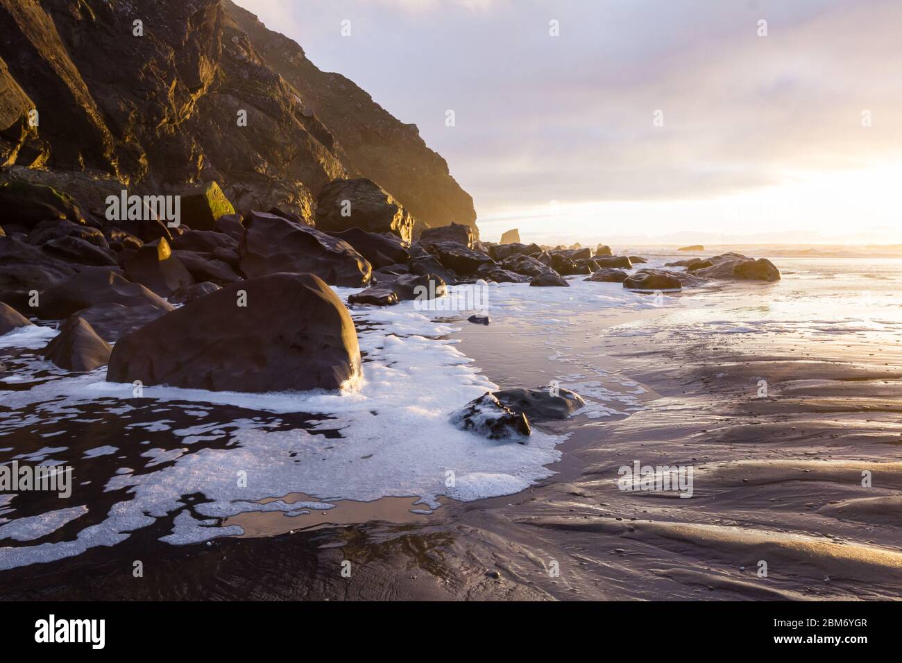Golden light reflecting on the rocks at Cape Sebastian as the sun drops ...