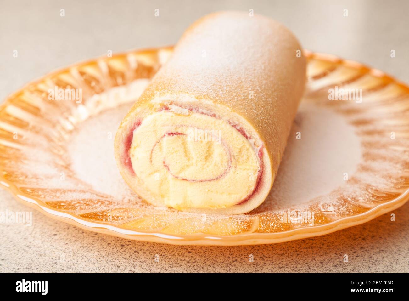 An Arctic Roll frozen desert dusted with caster sugar on a gold plate ...