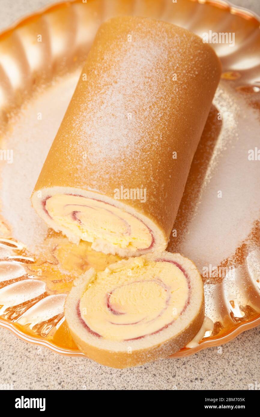 A sliced Arctic Roll frozen desert dusted with caster sugar on a gold ...