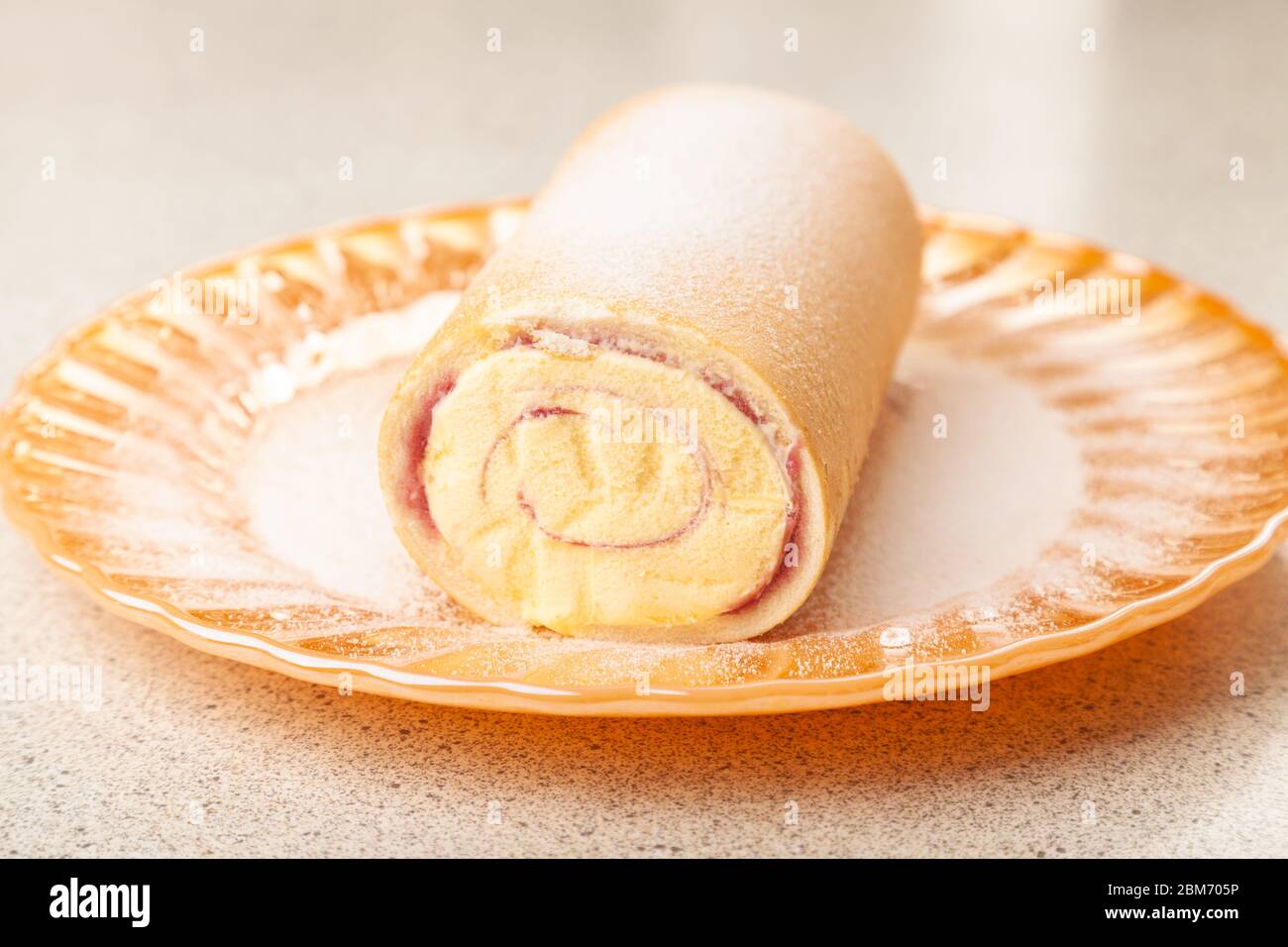 An Arctic Roll frozen desert dusted with caster sugar on a gold plate ...
