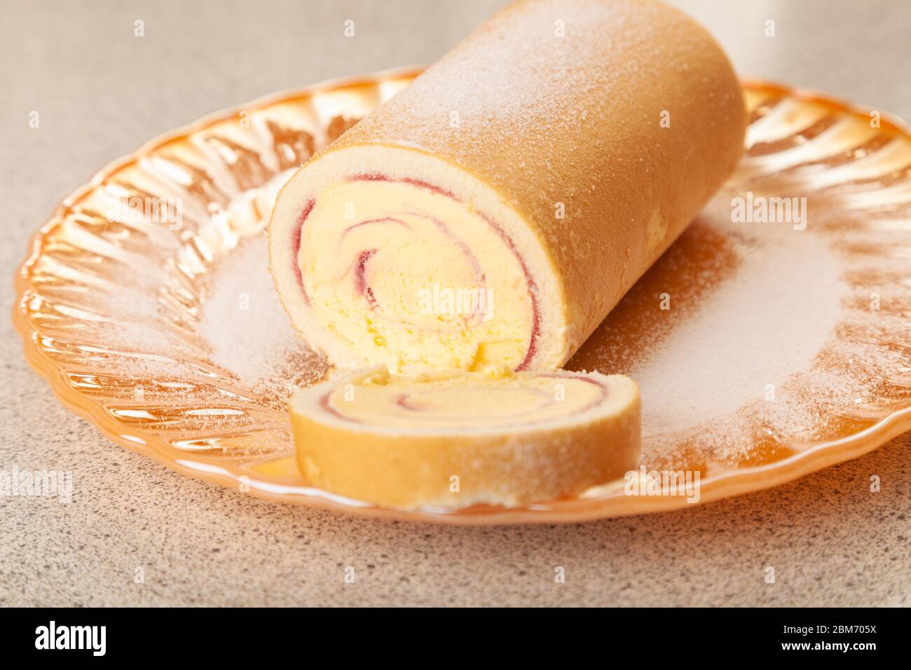 A sliced Arctic Roll frozen desert dusted with caster sugar on a gold ...