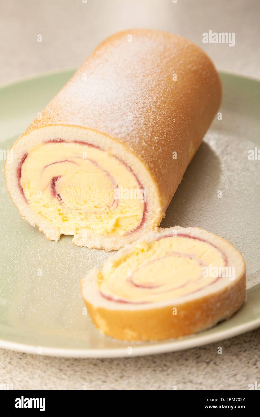 A sliced Arctic Roll frozen desert dusted with caster sugar on a green ...