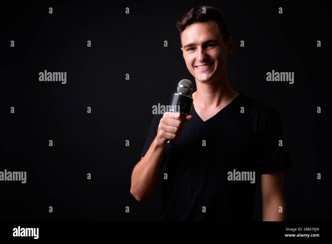 Portrait of happy young handsome man using microphone Stock Photo - Alamy