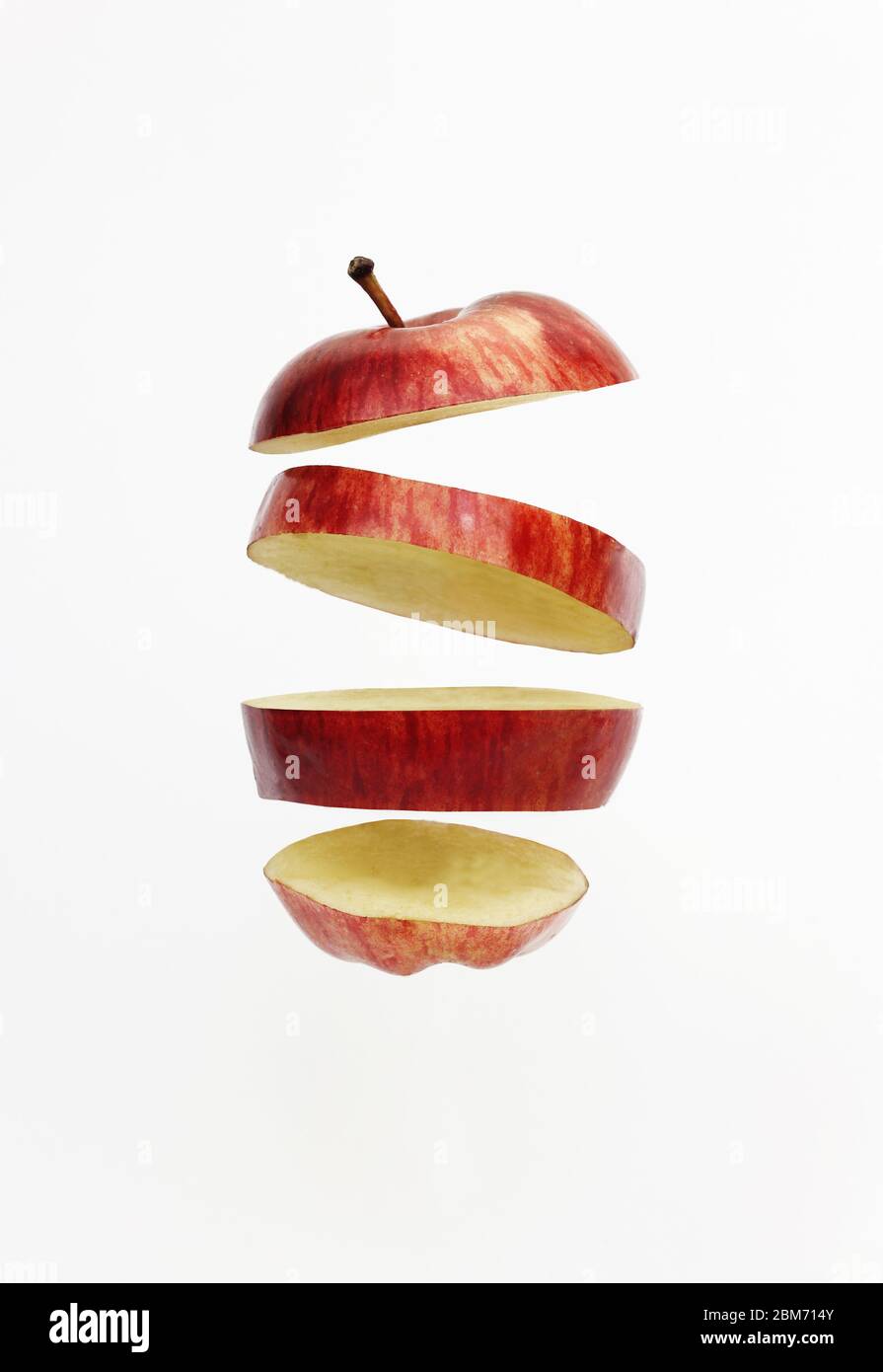 Fresh red golden delicious apple cut into slices floating isolated on ...