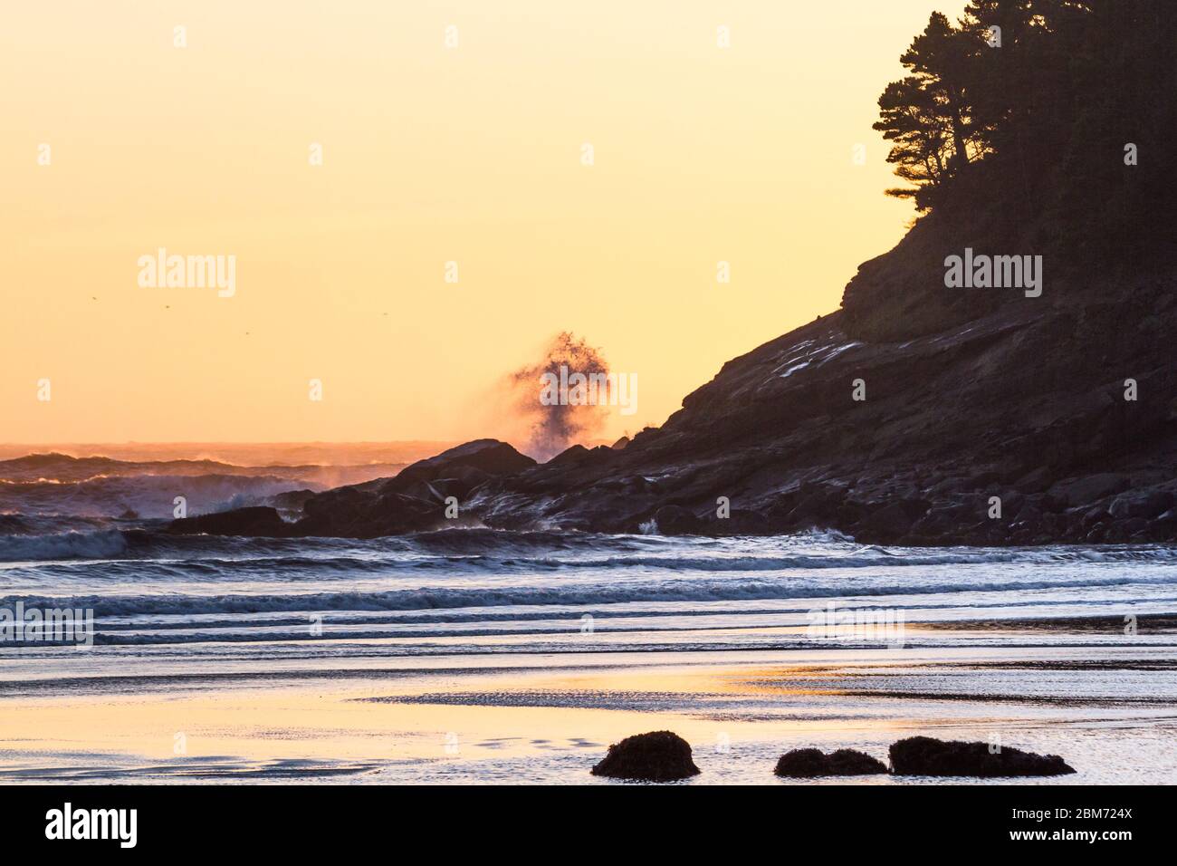 Orange skies and waves splashing on the rocks adding to an already ...