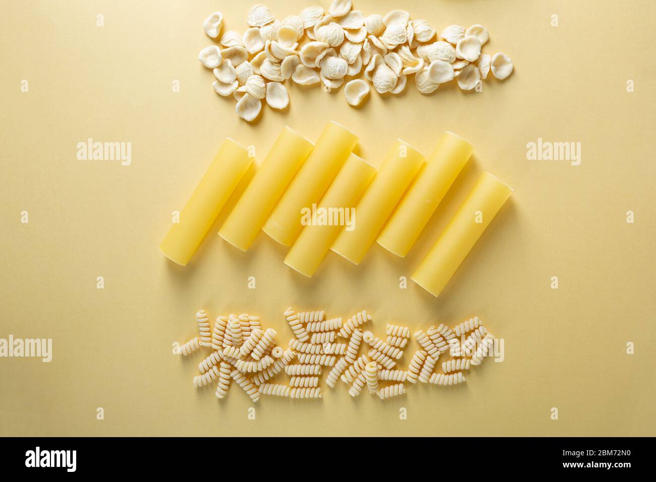Overhead view of dry pasta on yellow background Stock Photo - Alamy