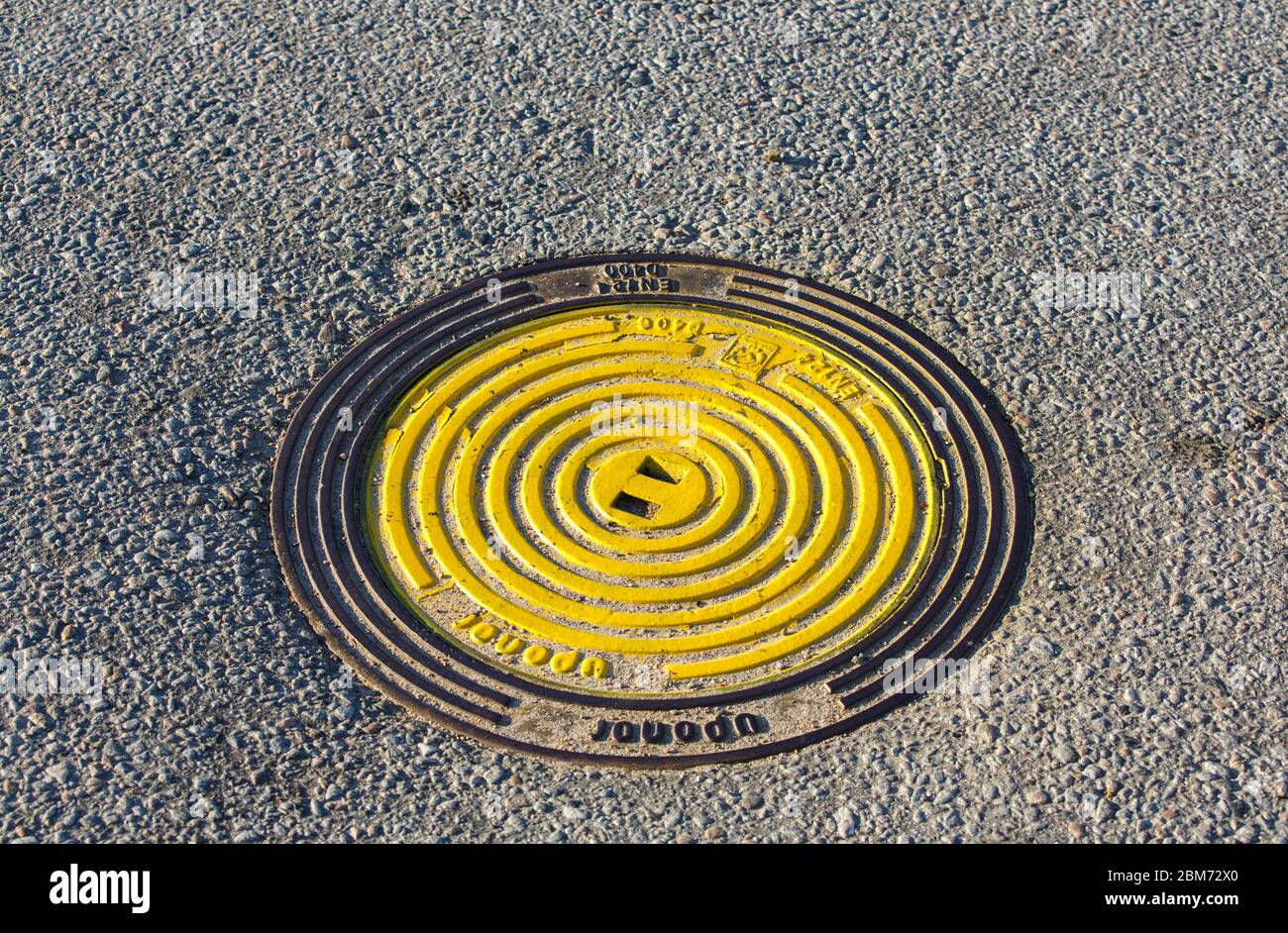 Closeup of a metallic round drainage manhole cover painted yellow ...