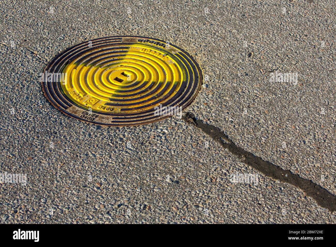 Closeup of a metallic round drainage manhole cover painted yellow ...