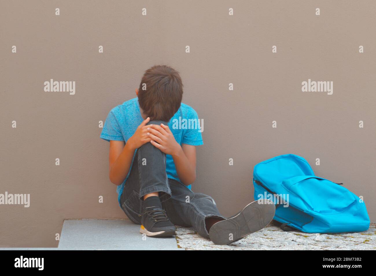 Sad child sitting alone near school on the ground outdoors Stock Photo ...