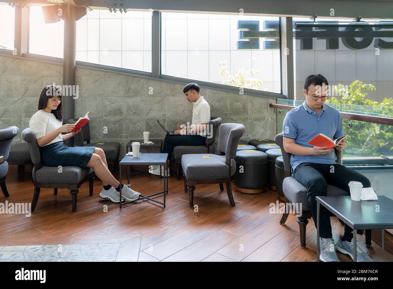 Asian young man and woman sitting one person per one table for distance ...