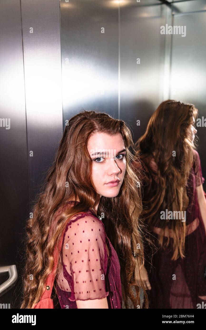 Young girl in elevator reflected in mirror on wall Stock Photo - Alamy