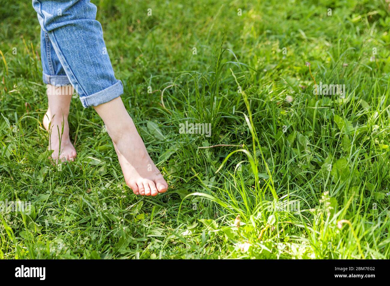Two beautiful female feet walking on grass in sunny summer morning ...