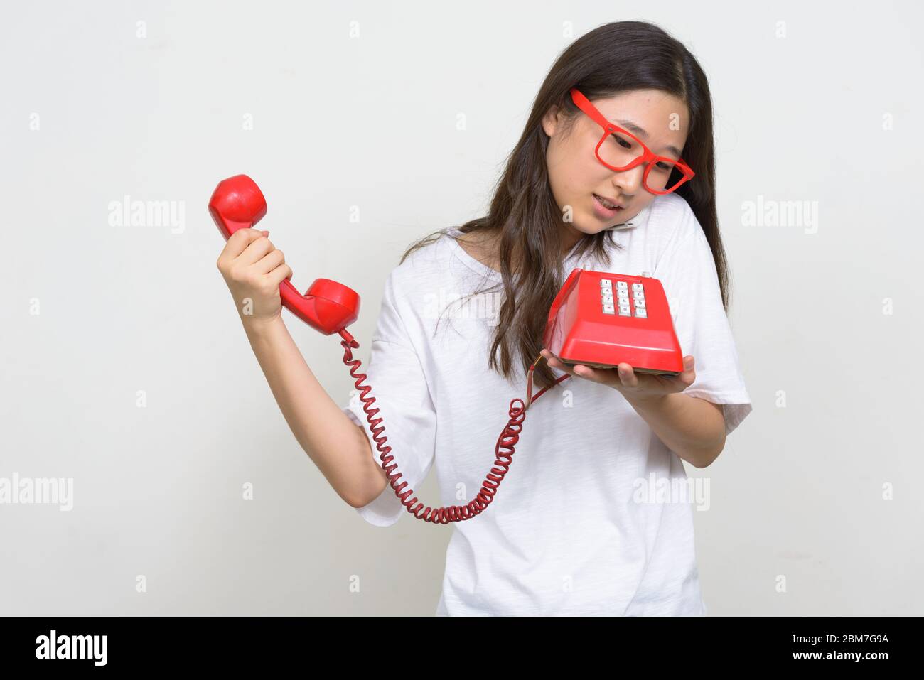 Portrait of young Asian nerd woman talking on mobile phone while ...