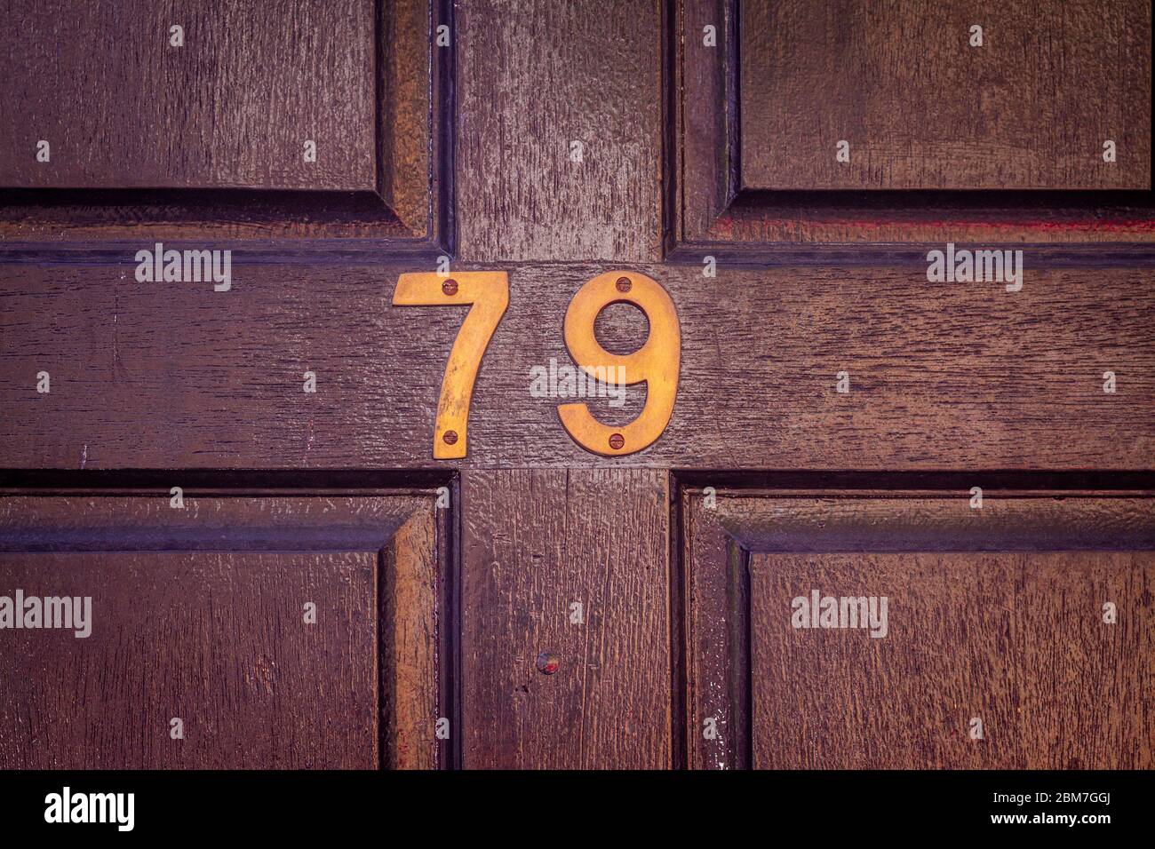 House number 79 on a dark varnished wooden front door Stock Photo - Alamy