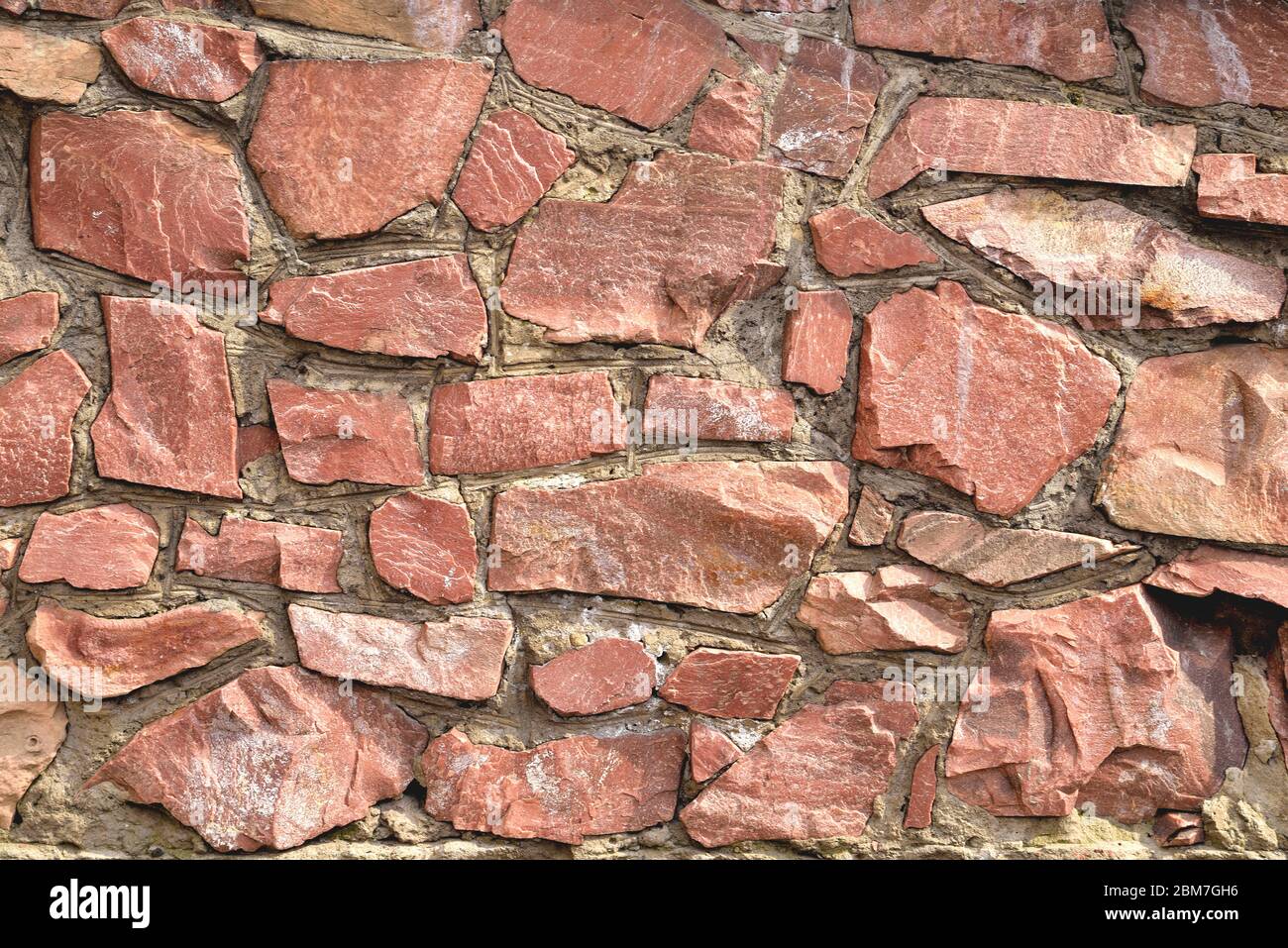 The wall of large raw granite stones of red color, background granite ...
