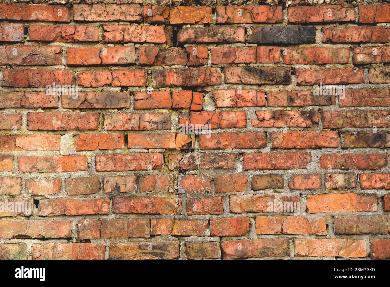 Old brick wall weathered and broken bricks, crack in the center ...