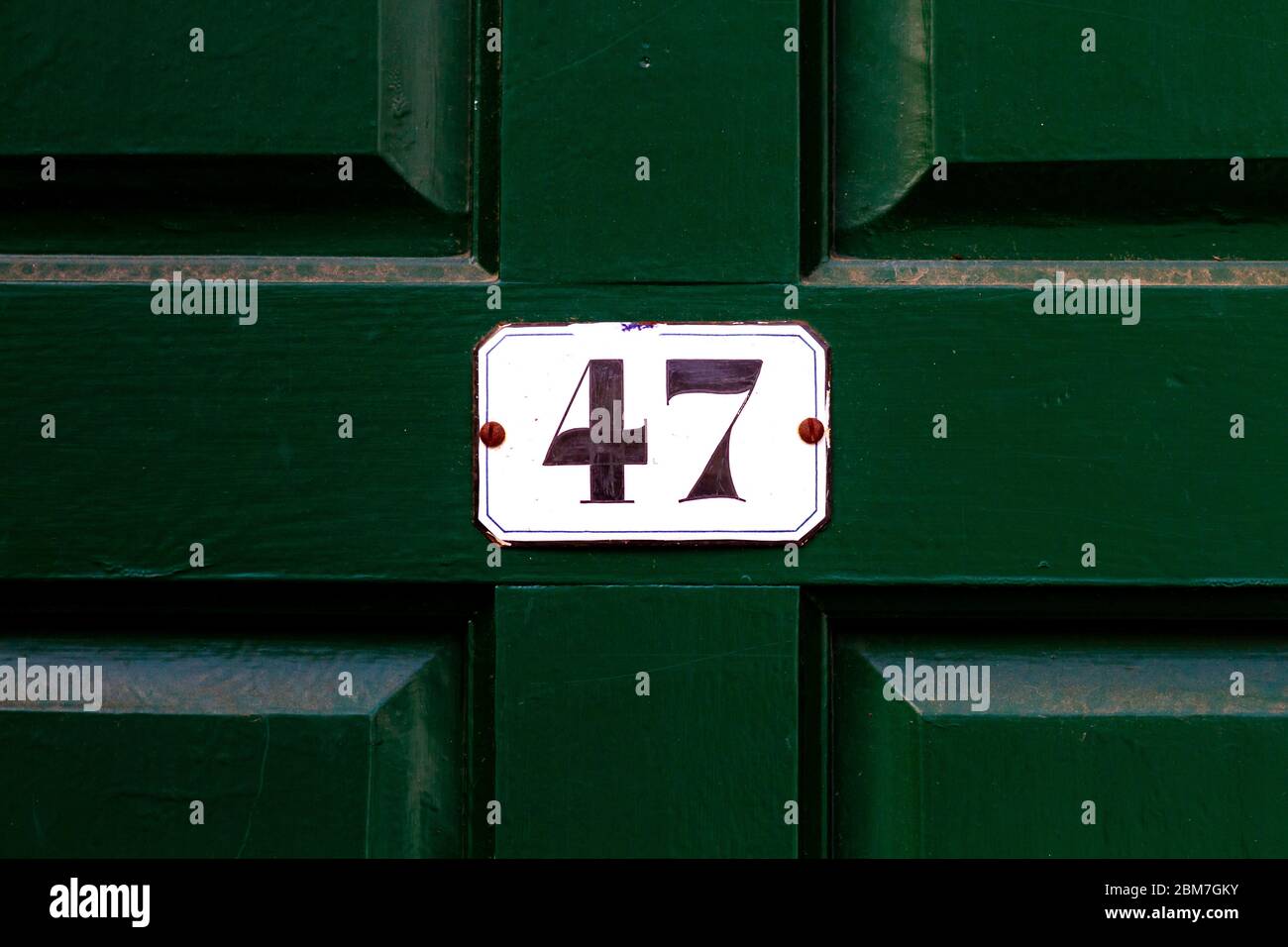 House number 47 on a white plaque on a dark green wooden front door ...