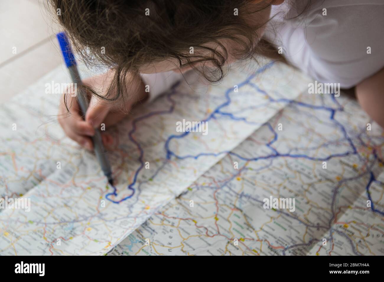 Hand of the child writing on a map with blue pen. Kids hand holding ...