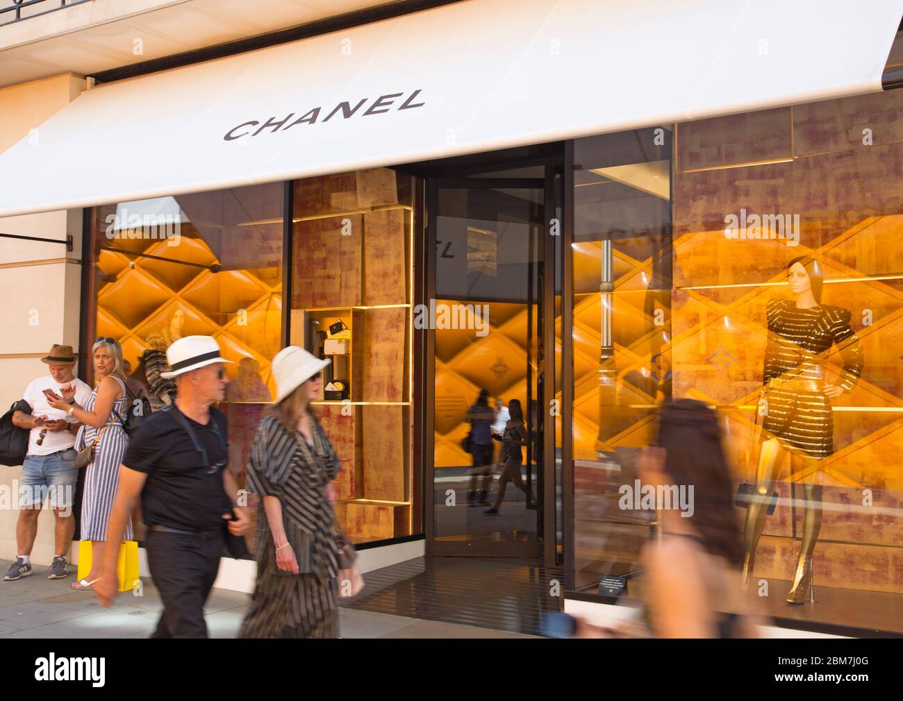 Smart looking summer shoppers walking past the Chanel luxury brand ...