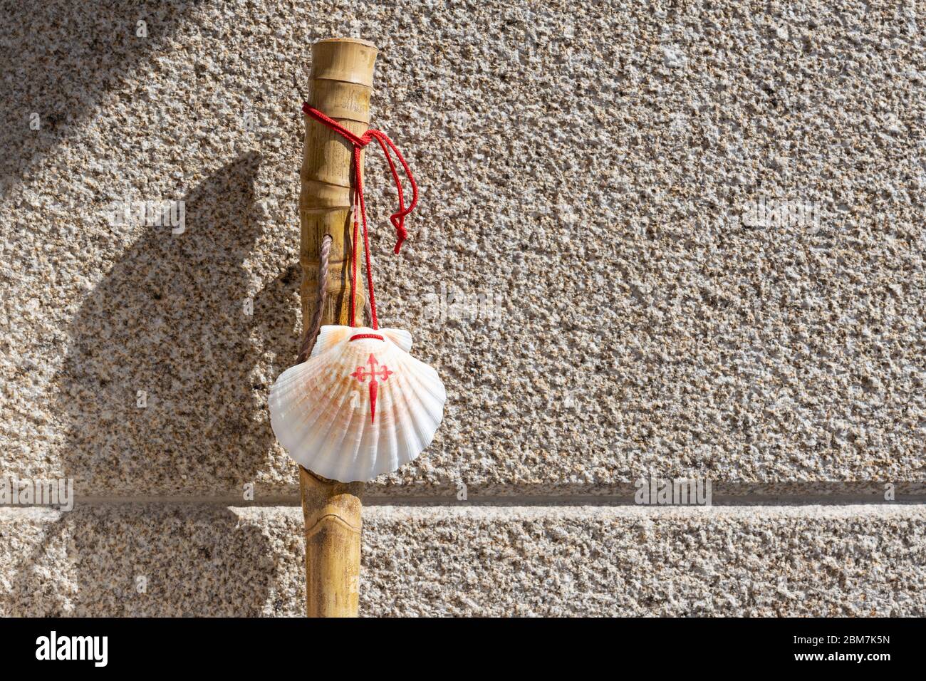 Walking stick and seashell of the Camino de Santiago leaning on granite ...