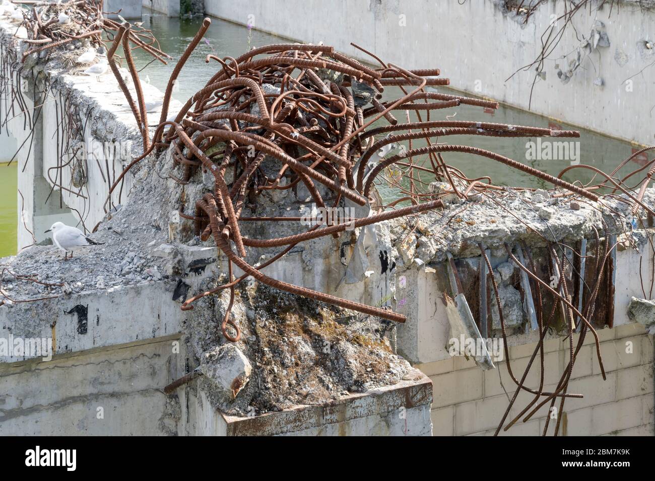 cityscape with warped reinforcing steel at flooded ruins of collapsed ...