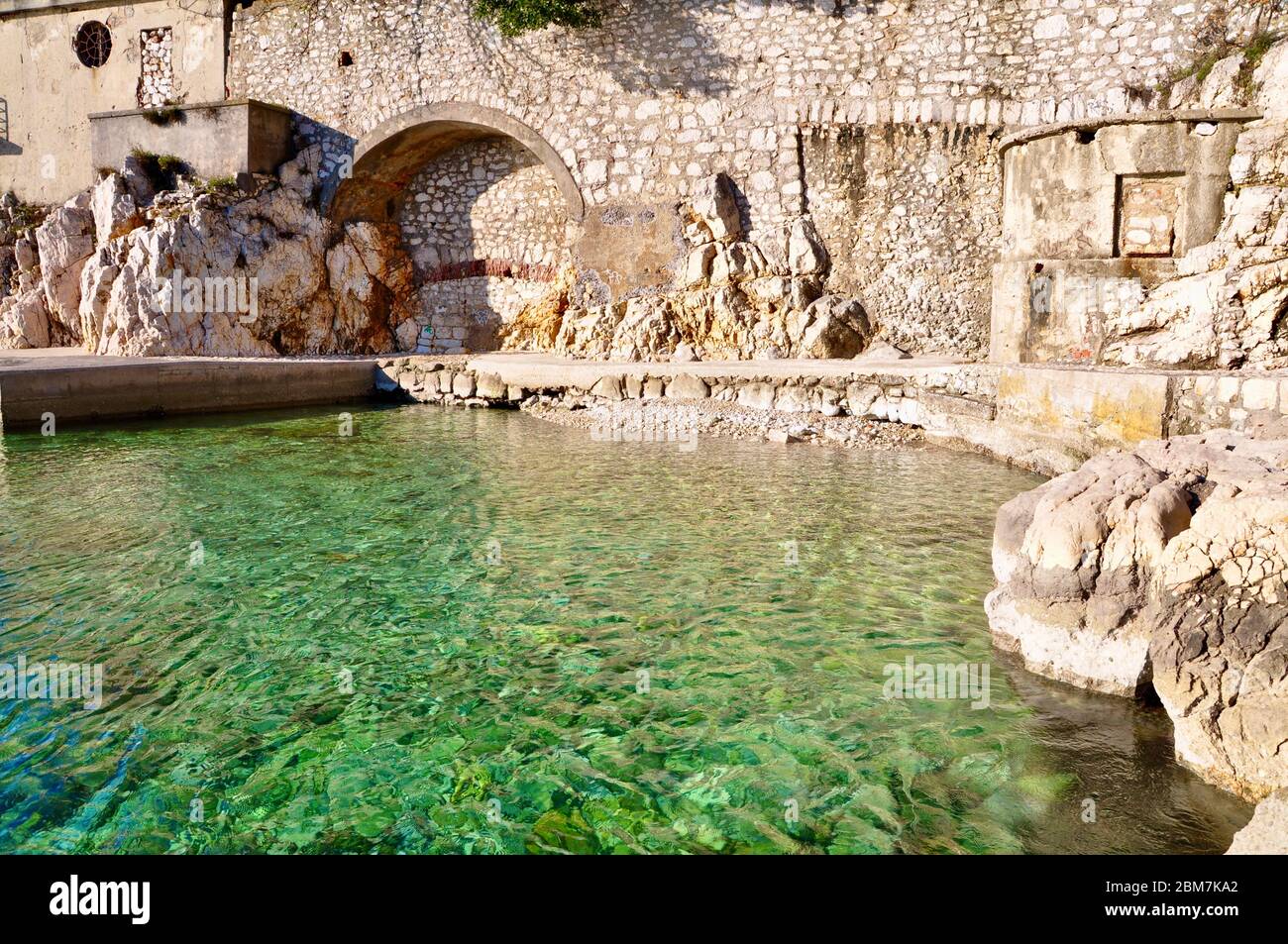 Rocky seashore on Croatia beach with turquoise water and pine trees.A ...