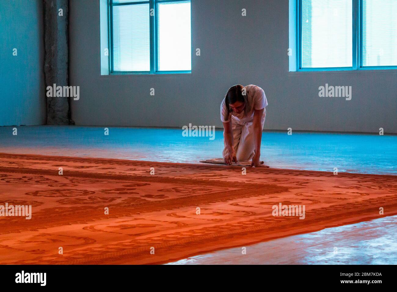 artist creating a red dirt rug with stamps at Artprize 9 Stock Photo ...