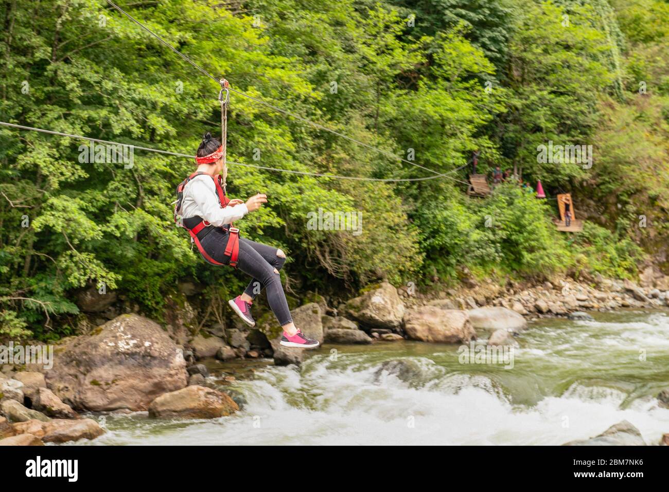 Rear view of tourist girl gliding on the zip line trip on Firtina ...
