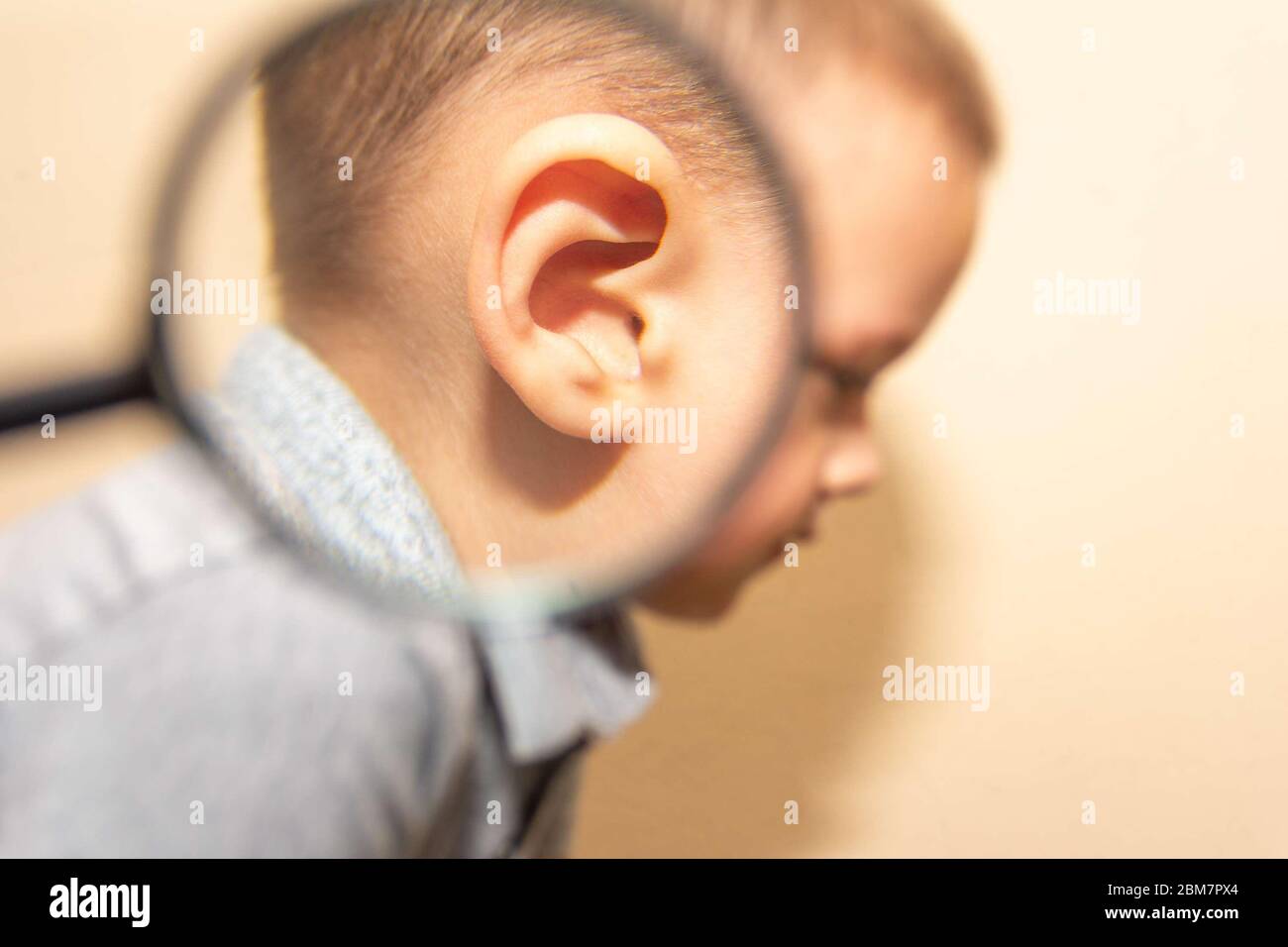 a child's ear magnified through a magnifying glass Stock Photo - Alamy