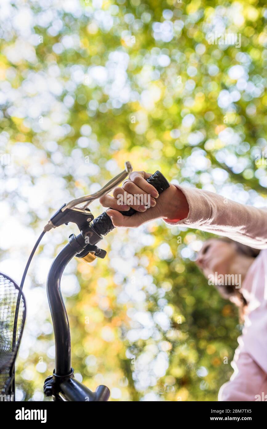 Woman riding a bike viewed from below with focus at her hand on the ...