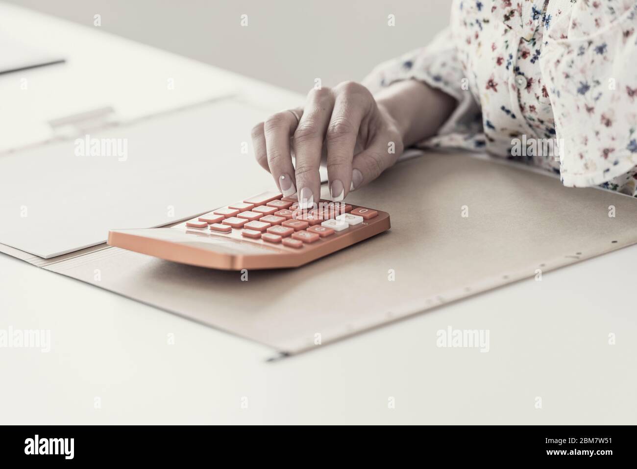 Female accountant calculating on orange desktop calculator, retro ...