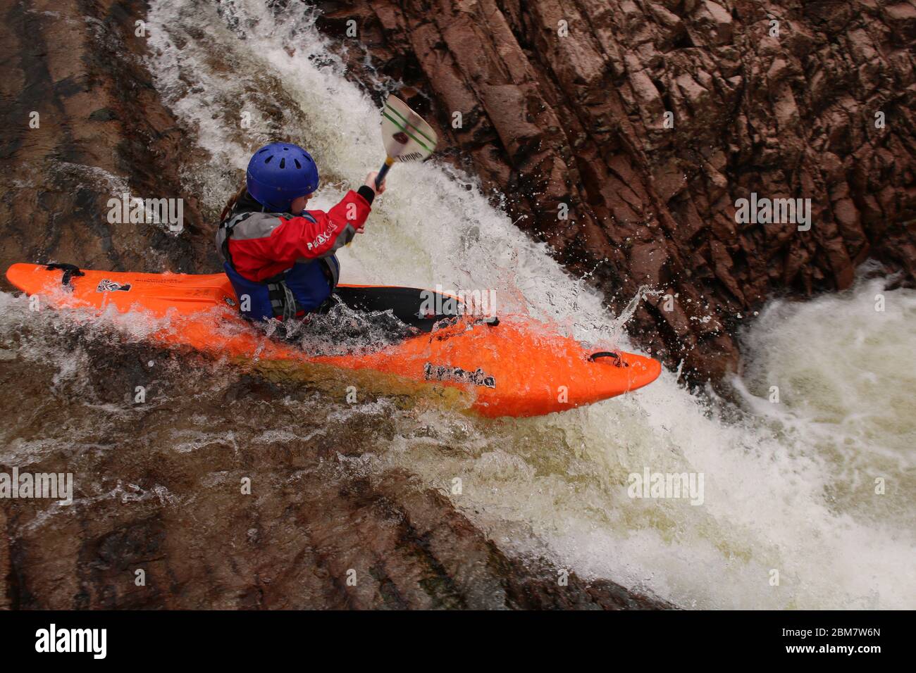 Female University Kayaker paddling over a waterfall (Triple Step) in a ...