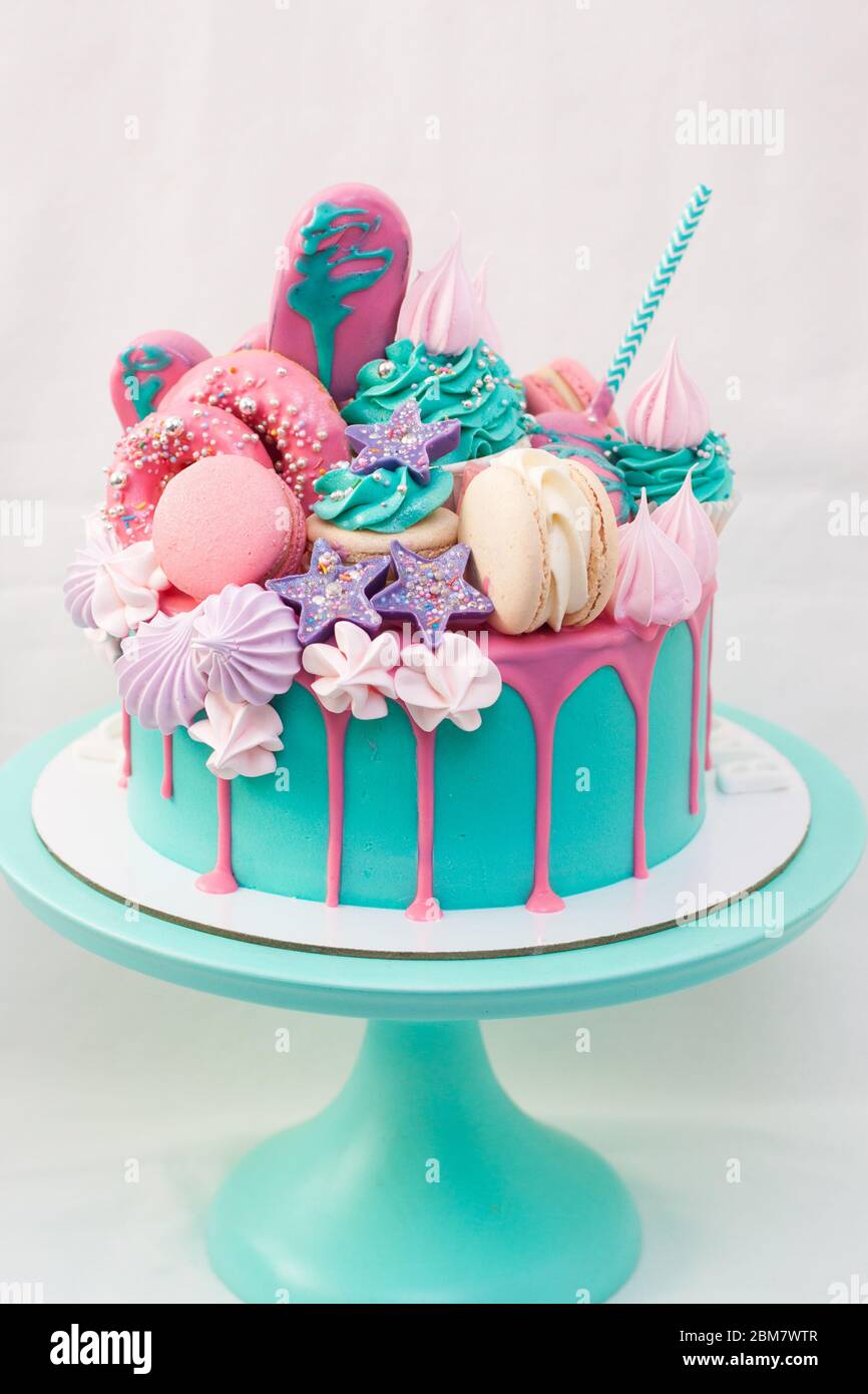 Pink and turquoise cake decorated with macaroons, cupcakes, cake pops ...