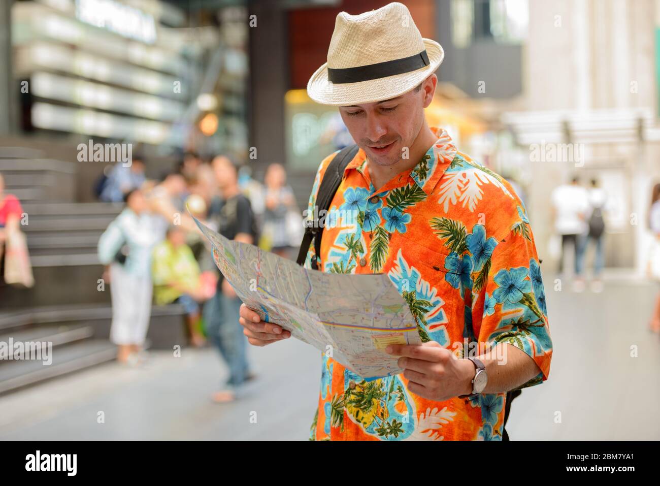 Young handsome tourist man with backpack reading map in the city ...