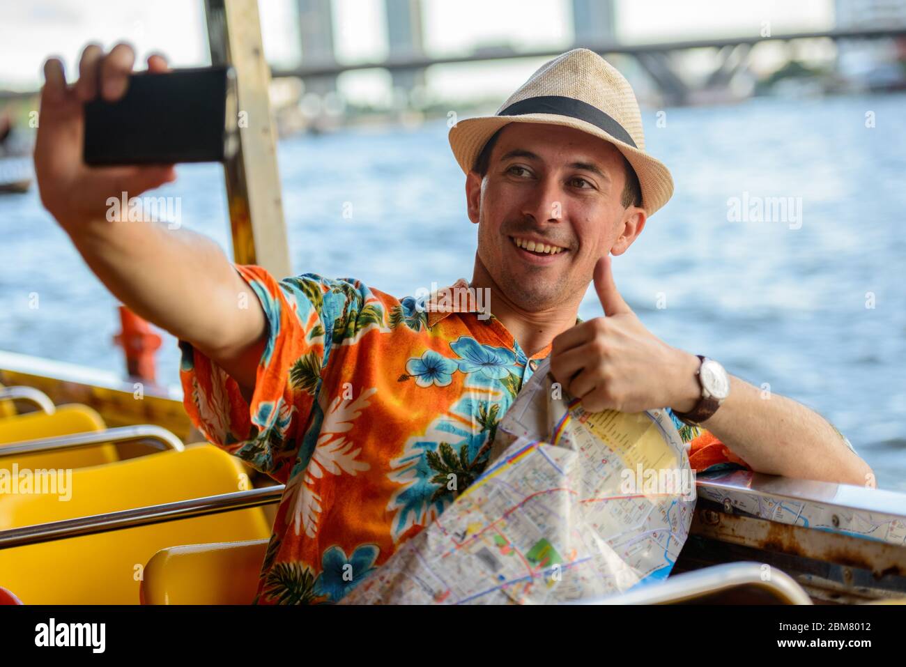 Happy young handsome tourist man taking selfie while riding boat on the ...