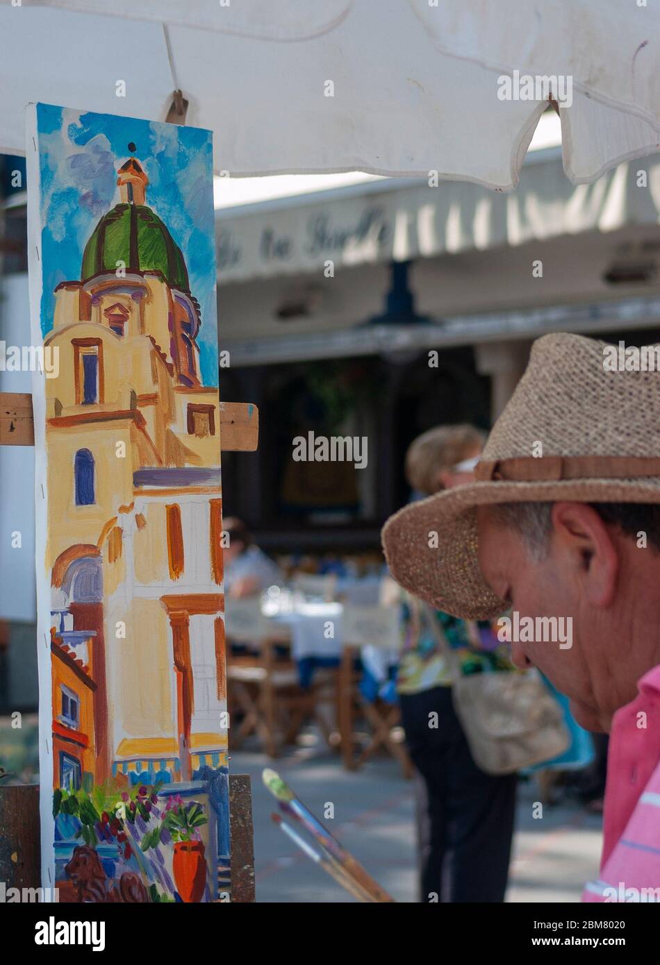 Artist on the streets of Positano painting a picture of the majolica ...