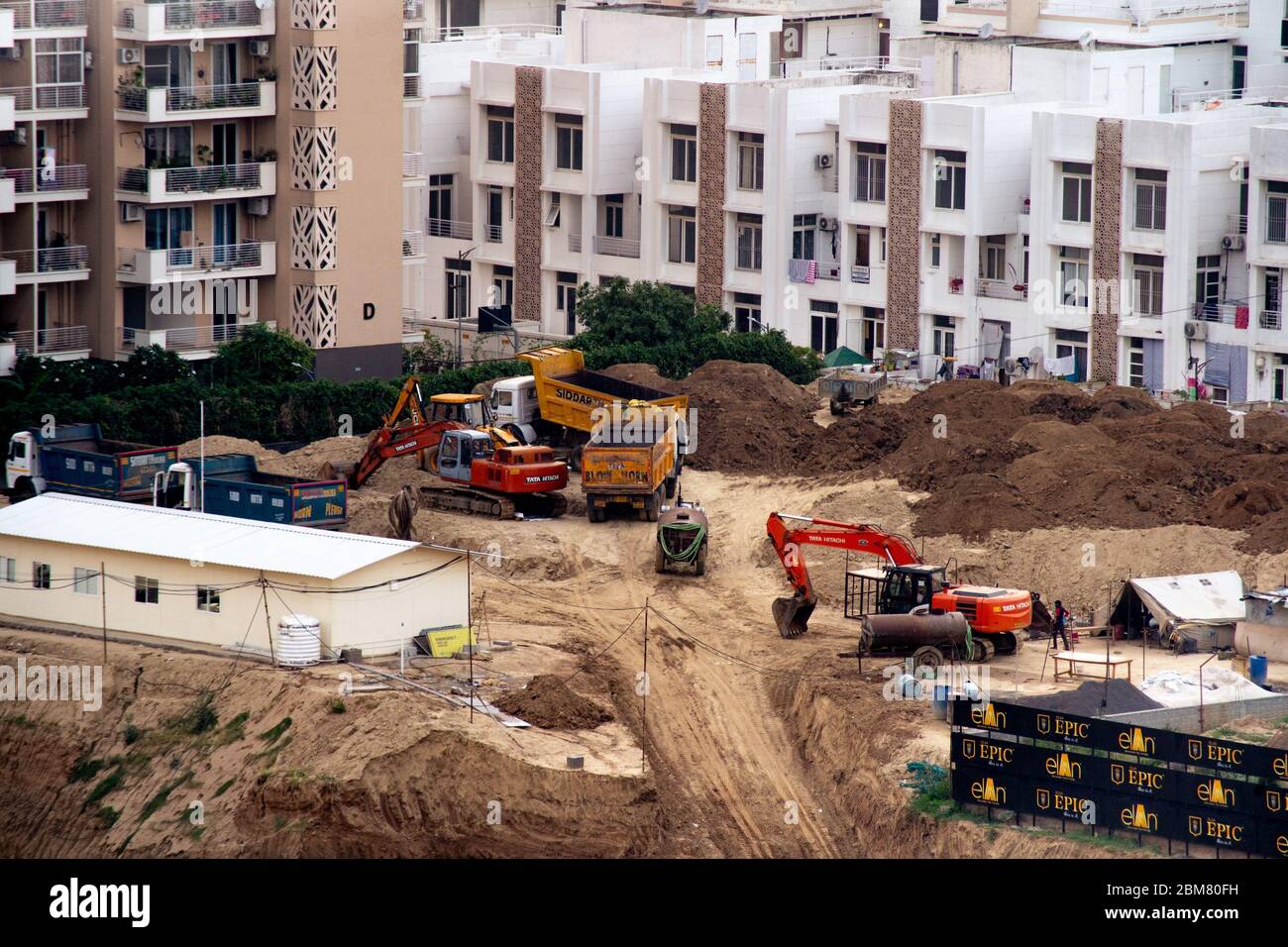 Excavator climbing a ramp to the parking area with other construction ...