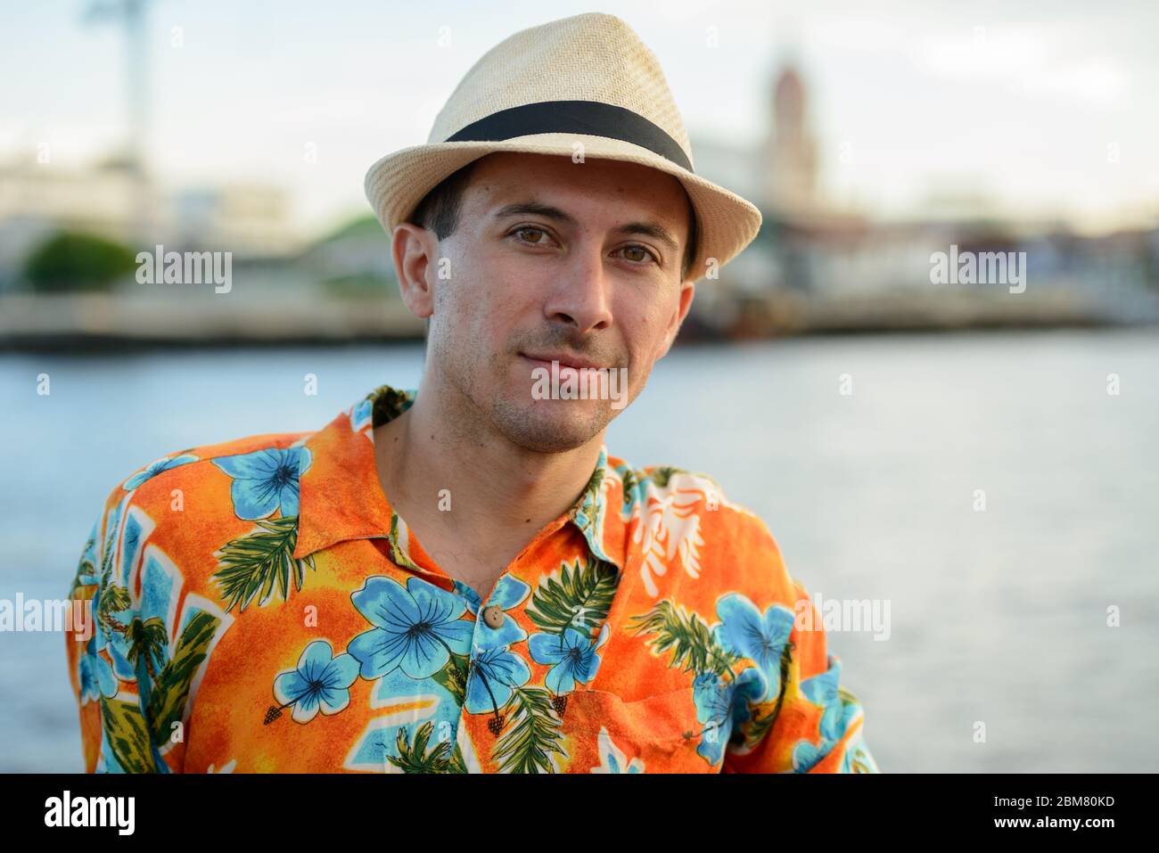 Young handsome tourist man thinking at pier against view of the river ...