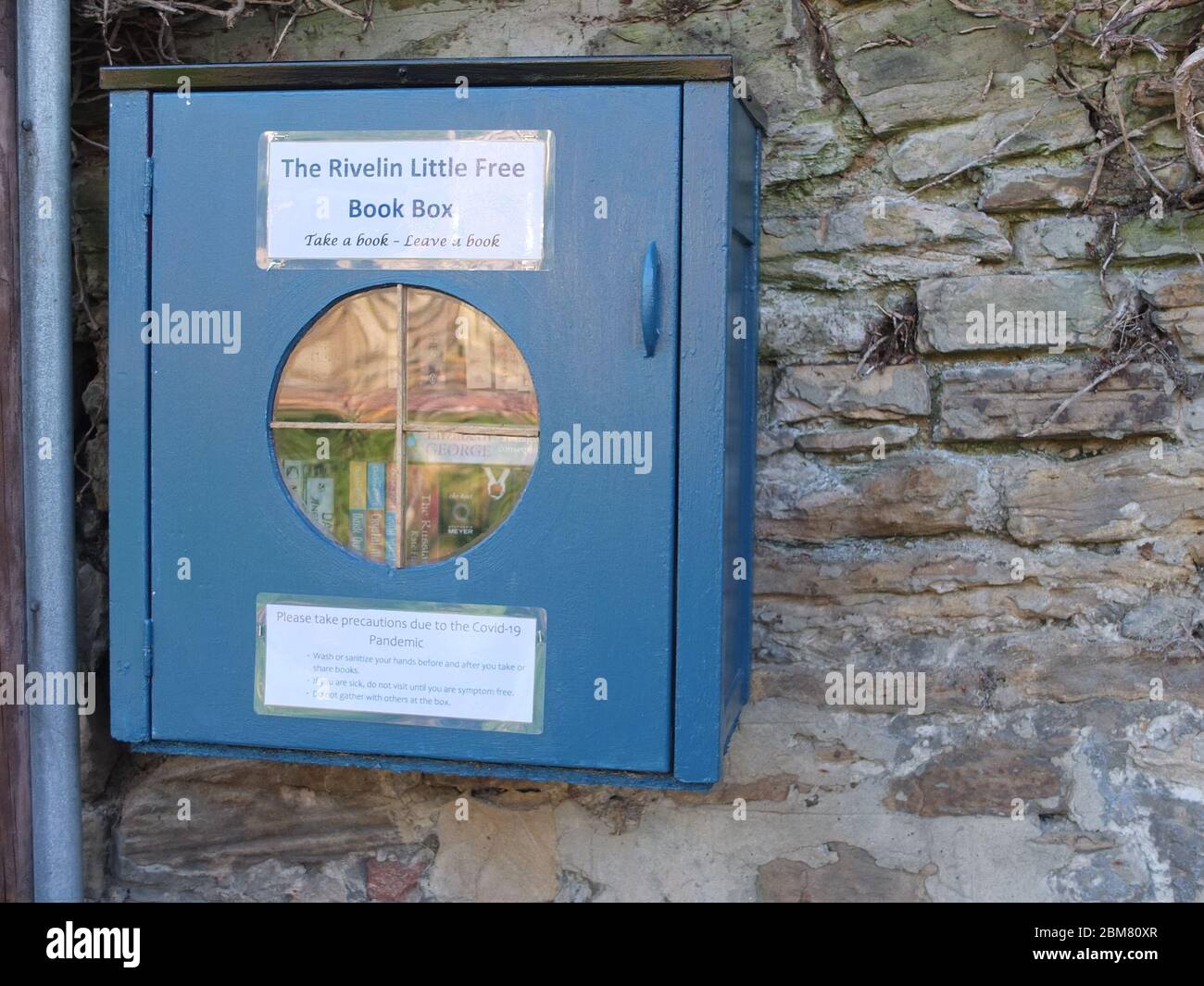 A box containing a free book exchange set up on the wall of a house in ...