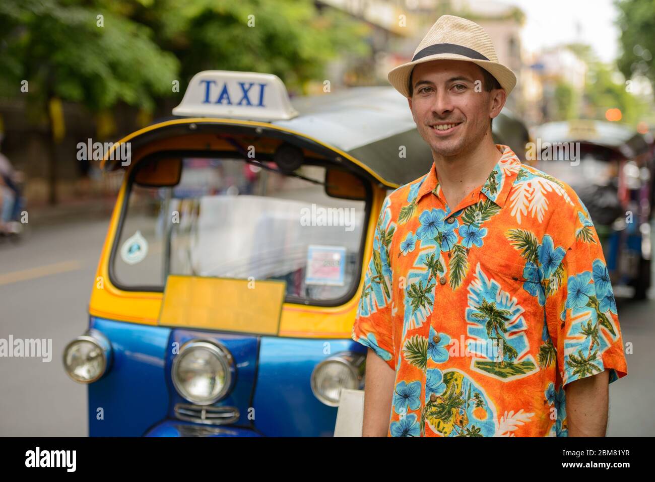 Happy young handsome tourist man with tuk tuk in Bangkok city Stock ...