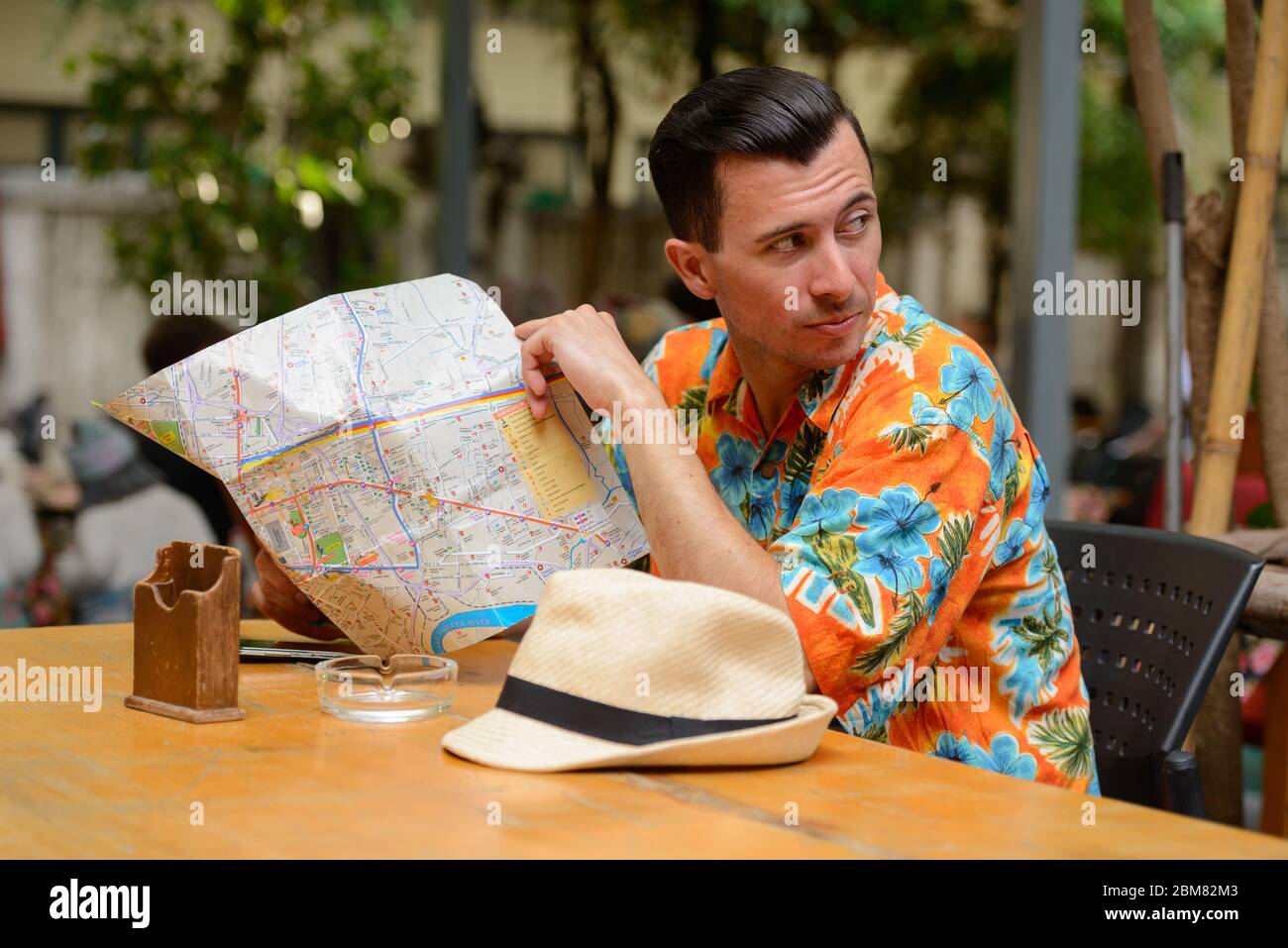 Young handsome tourist man reading map at the restaurant Stock Photo ...