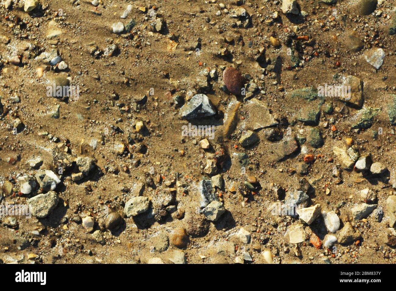 Small stones and sand. The natural texture of the soil. Shore of a ...