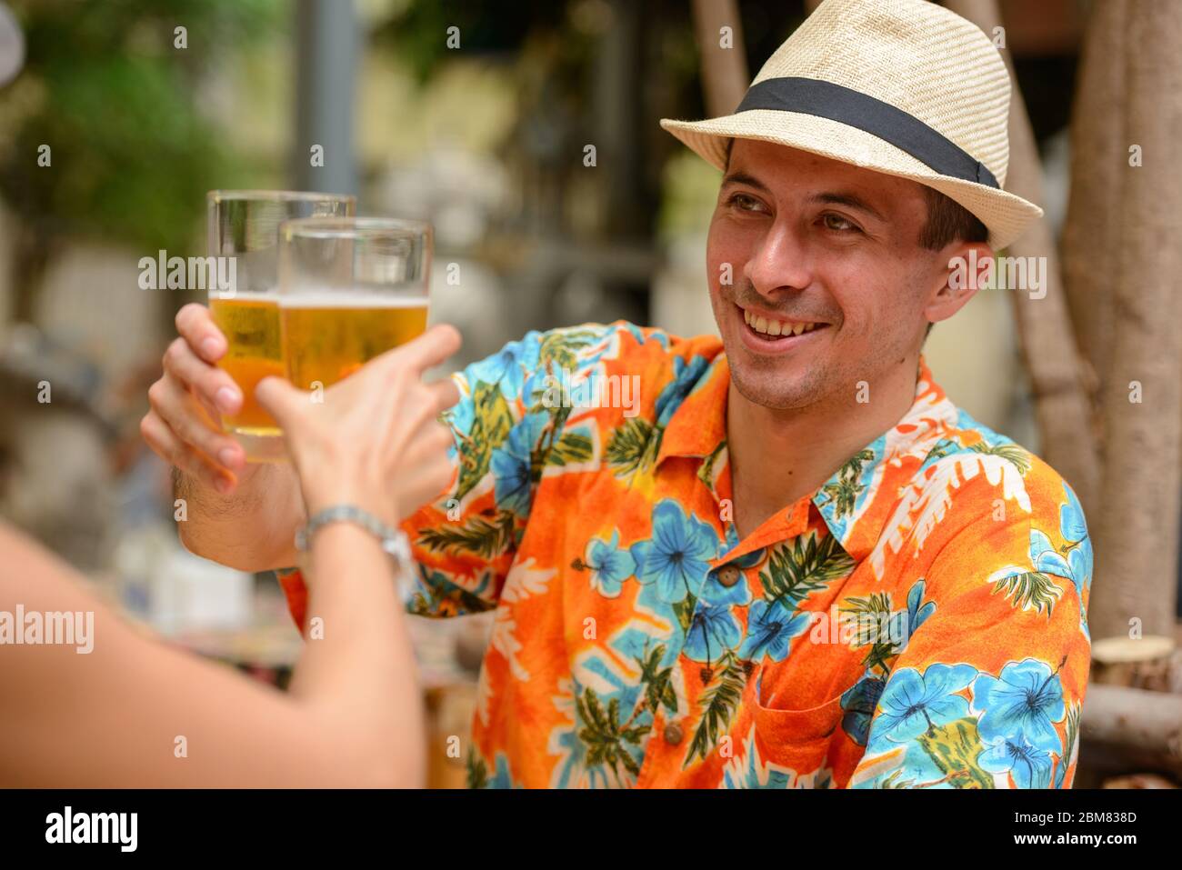 Happy multi ethnic tourist couple drinking beer together at restaurant ...