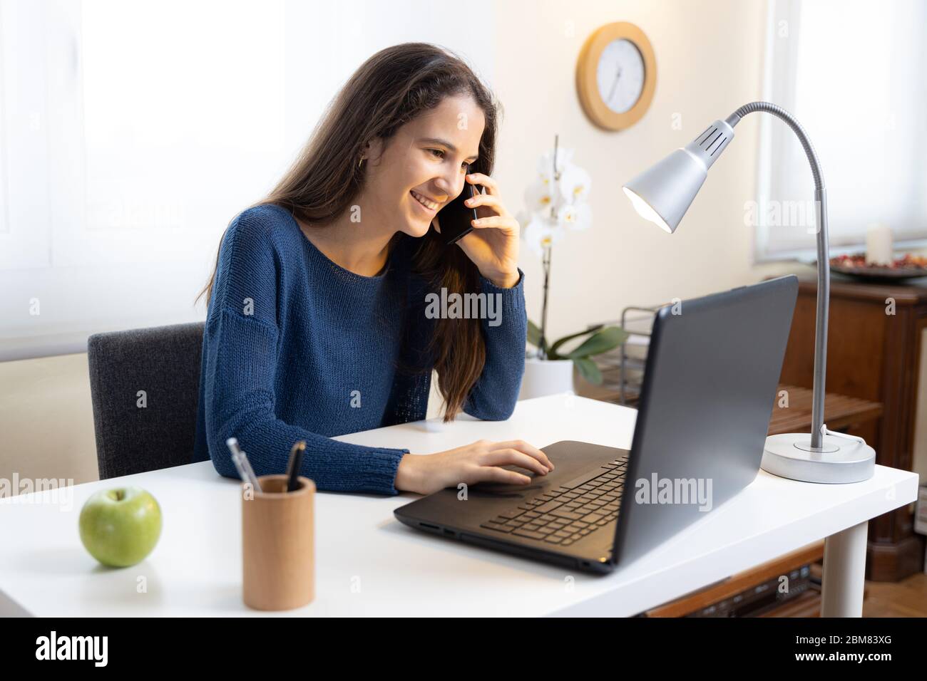 Happy student talking on a phone call checking a laptop Stock Photo - Alamy
