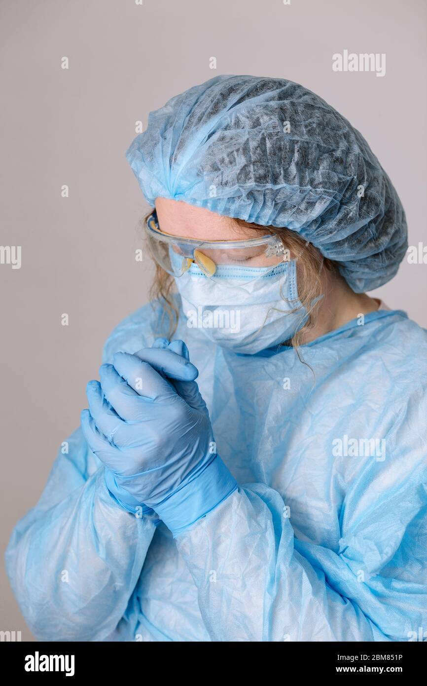 Praying tired doctor. Tired nurse at the hospital. The fight against ...