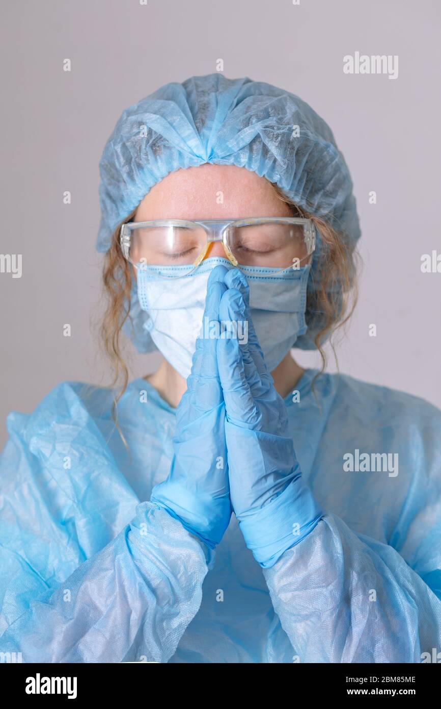 Praying tired doctor. Tired praying nurse at the hospital. The fight ...