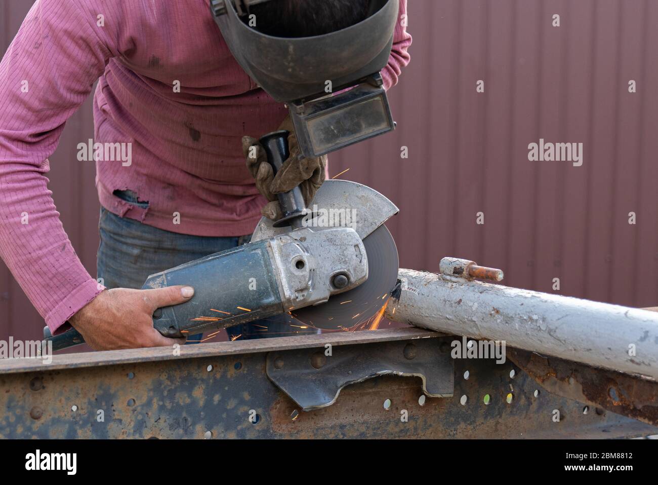 A close-up of a car mechanic using a metal grinder to cut a car bearing ...