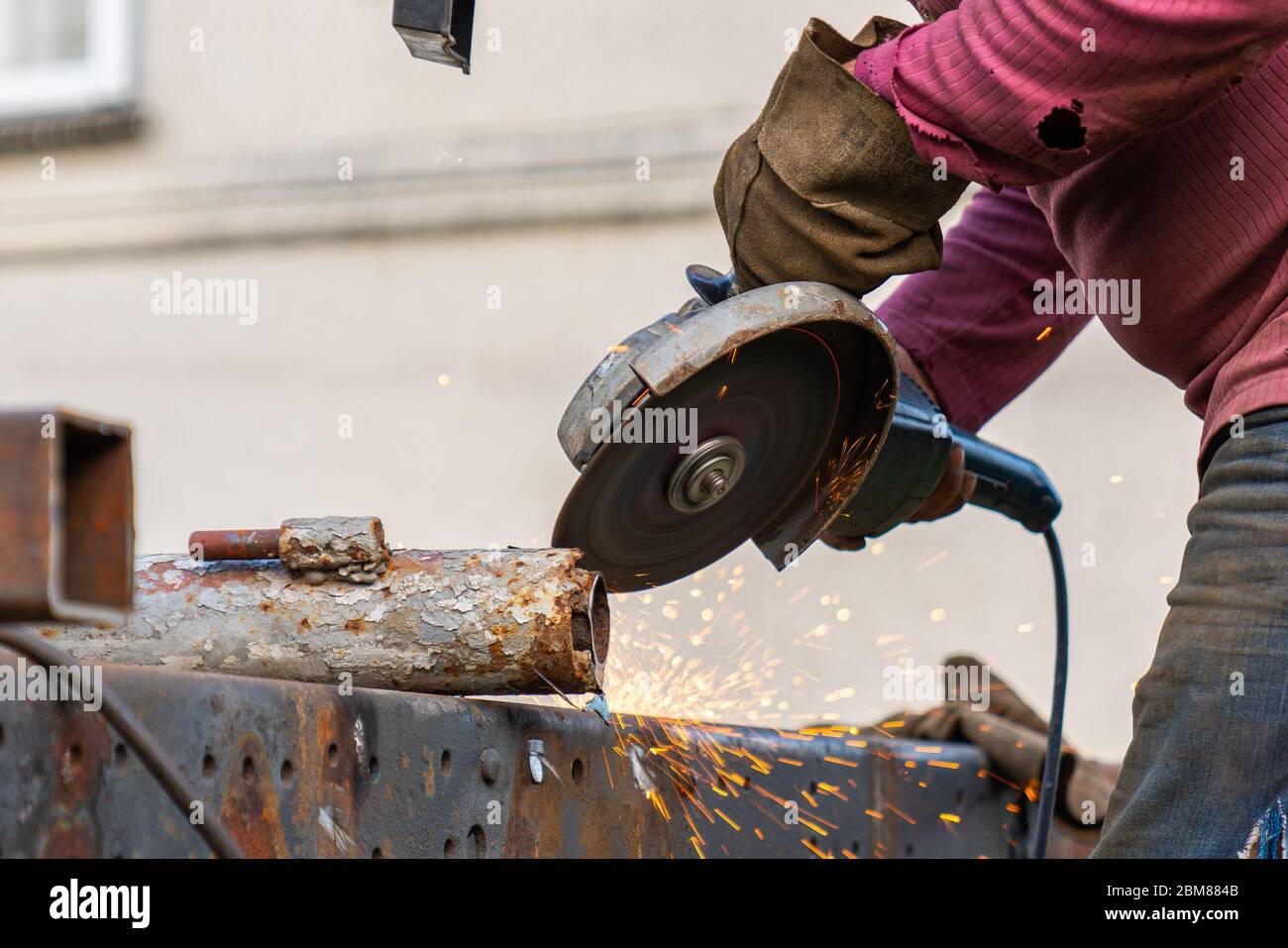 Industrial worker cutting and welding metal with many sharp sparks ...