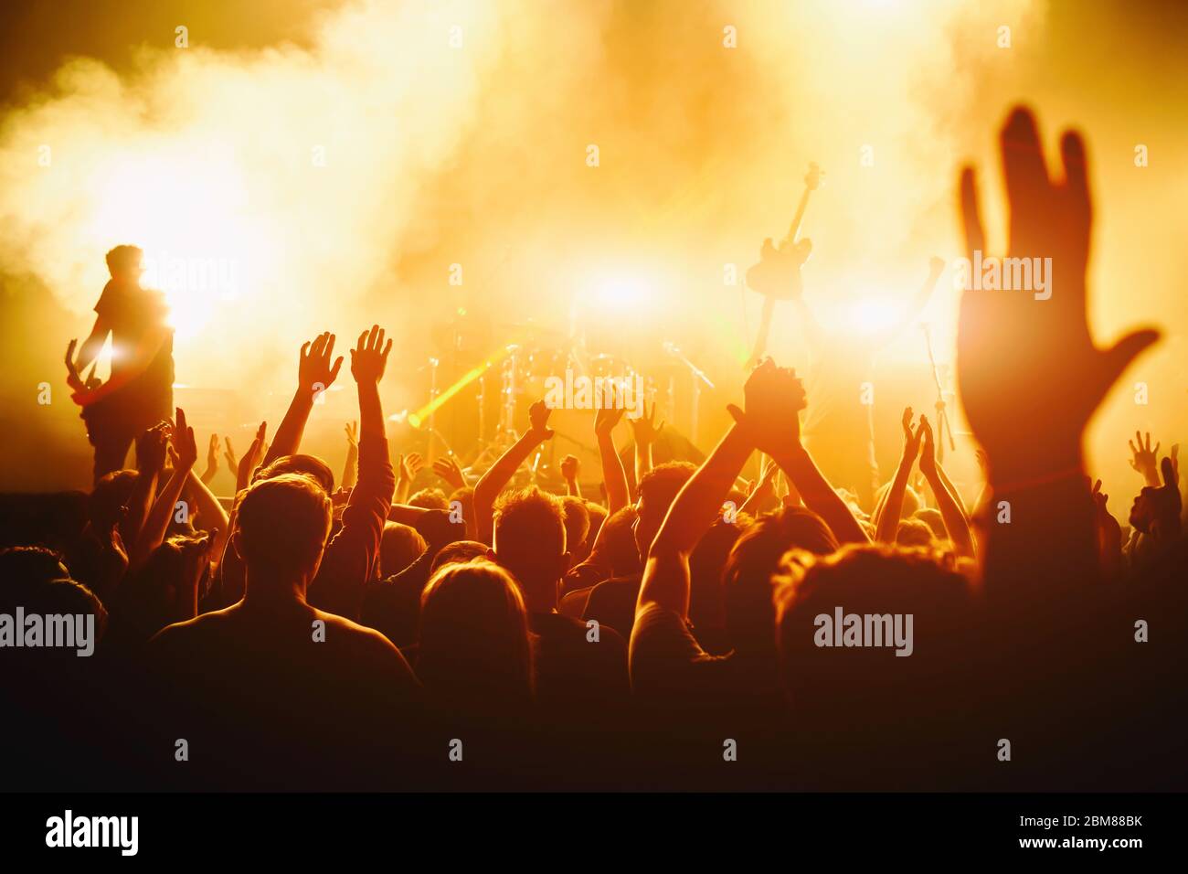 Rock concert, cheering crowd in front of bright colorful stage lights ...