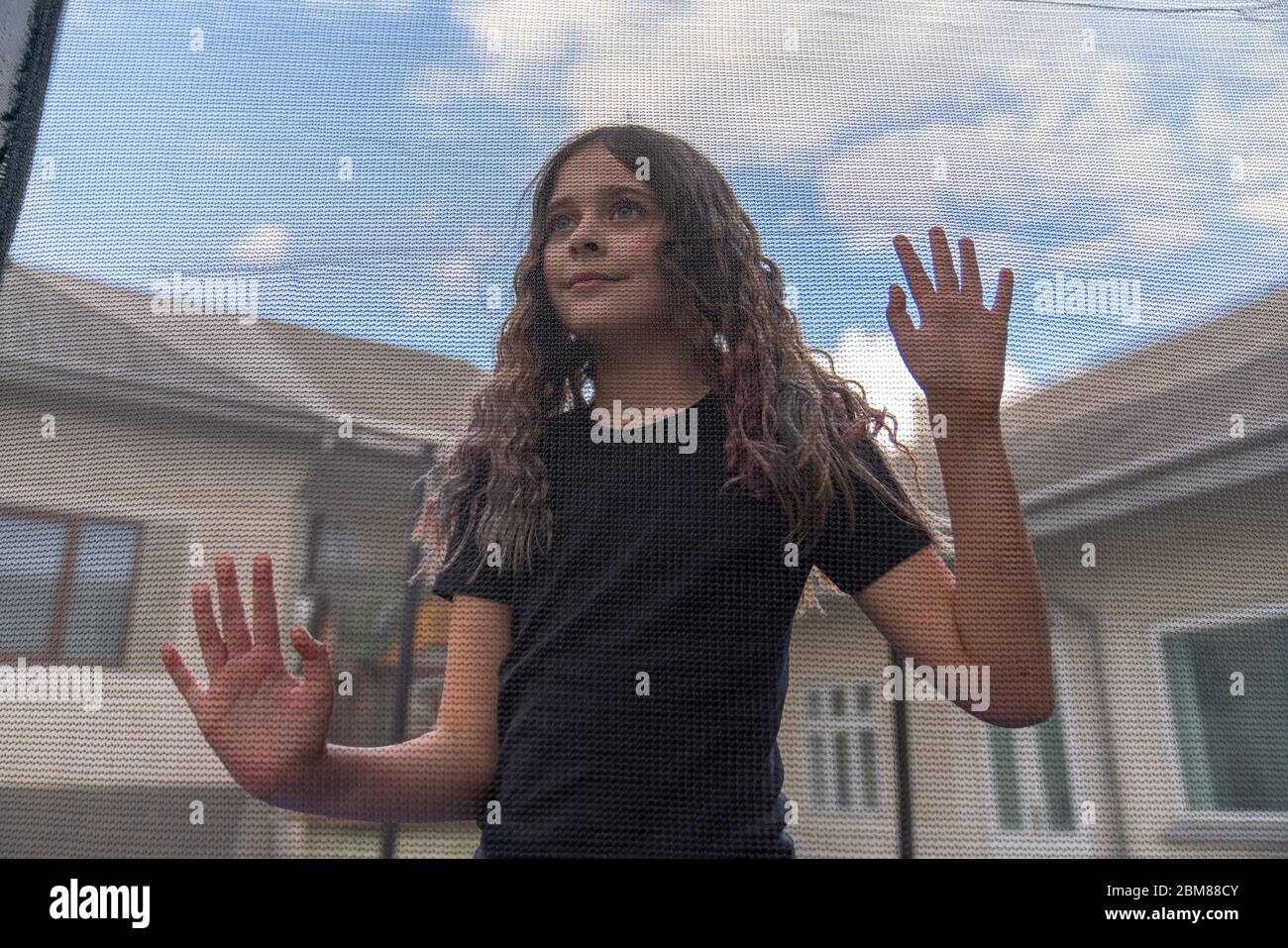 Waist up photo of a curly brunette girl in black t-shirt behind the ...
